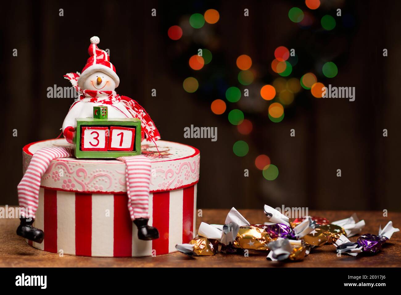 A snowman figure is sitting on a striped decoupage box showing a number ...