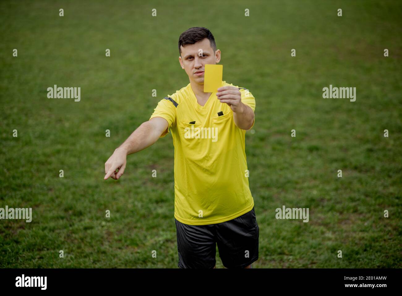 Angry football referee showing a yellow card and pointing with his hand ...