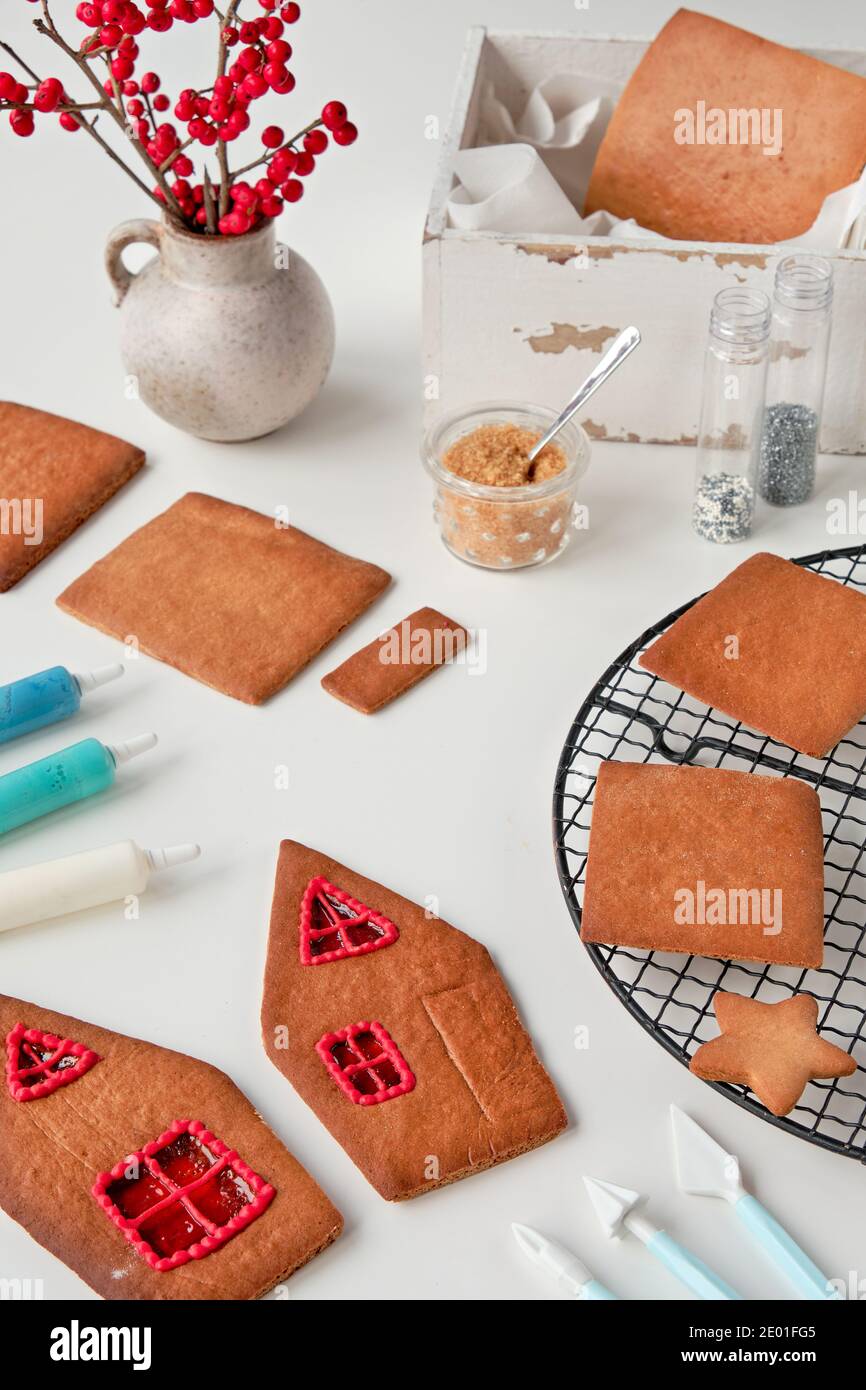 Making of gingerbread house, baked details arranged on white background ...