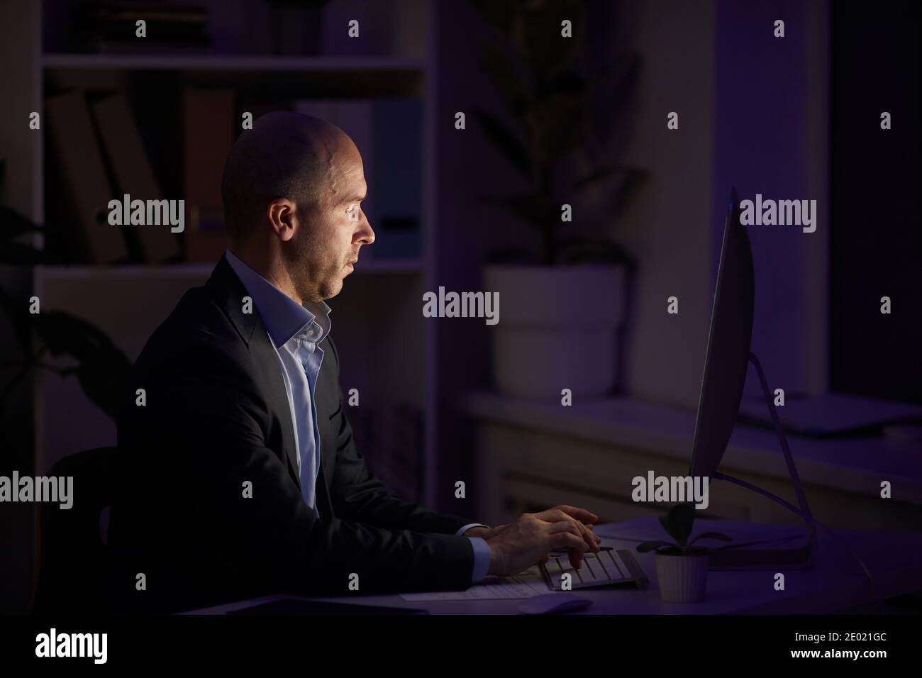 Side view shot of serious Caucasian man sitting alone in office room ...