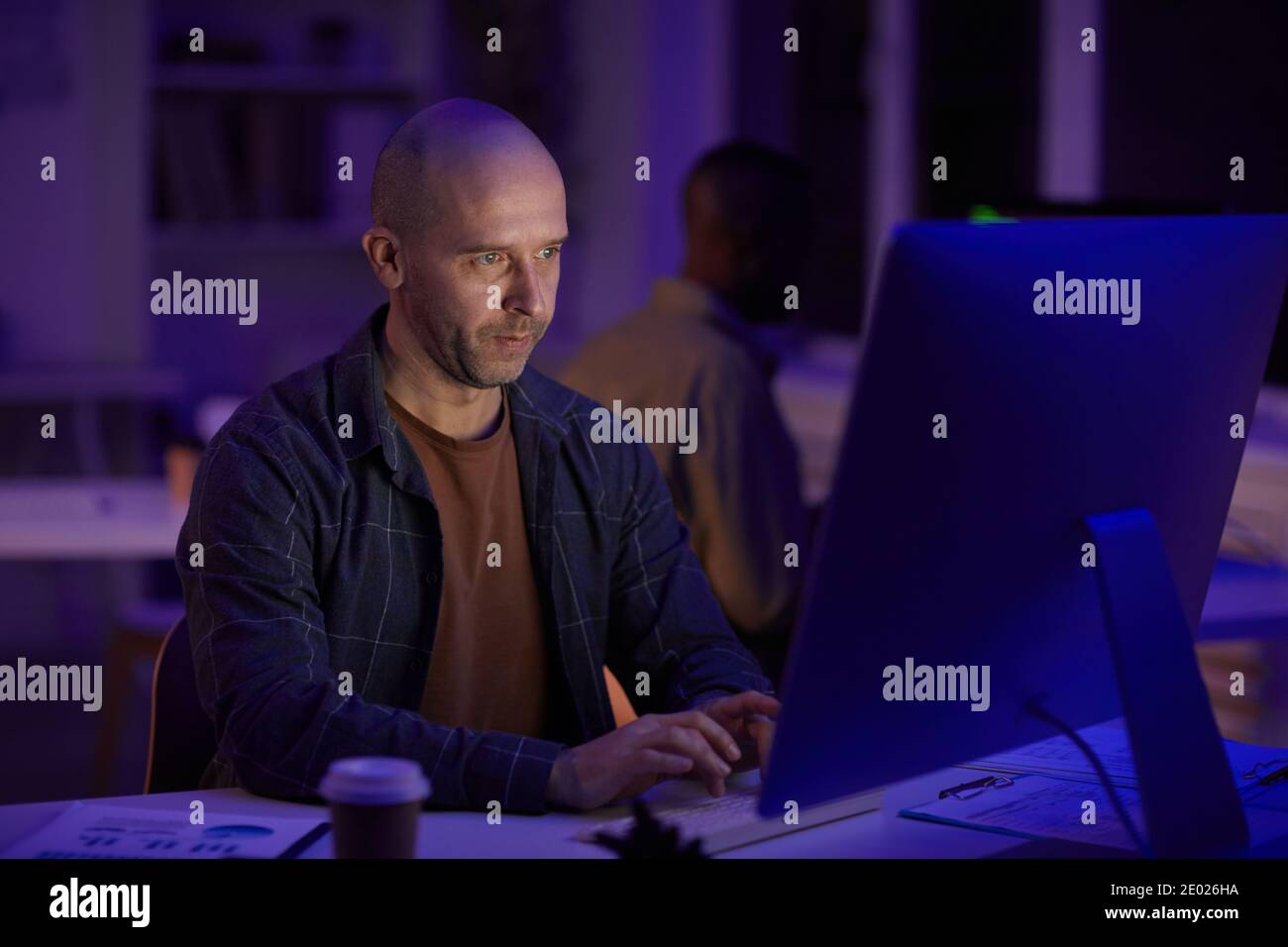 Mature Caucasian man wearing casual outfit sitting in front of computer ...