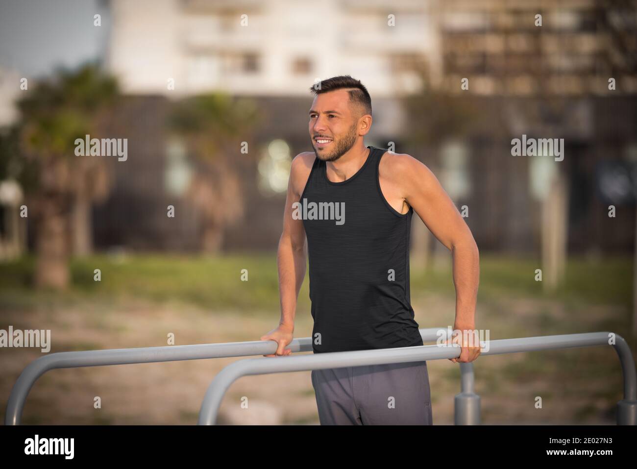 Fit young man doing triceps dips on parallel bars outdoors. Doing ...