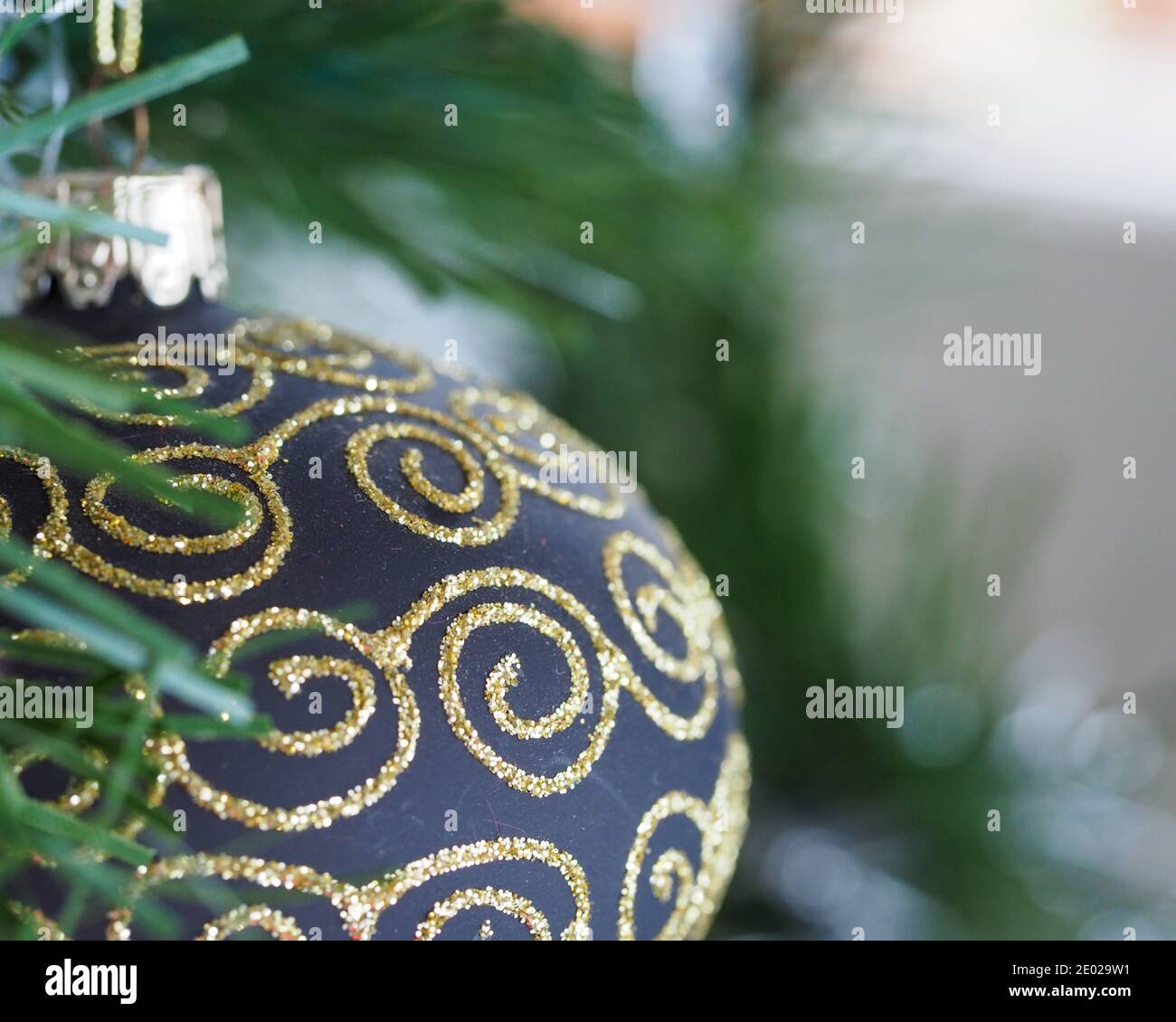 Christmas decoration, a sparkly black bauble with gold swirling glitter ...