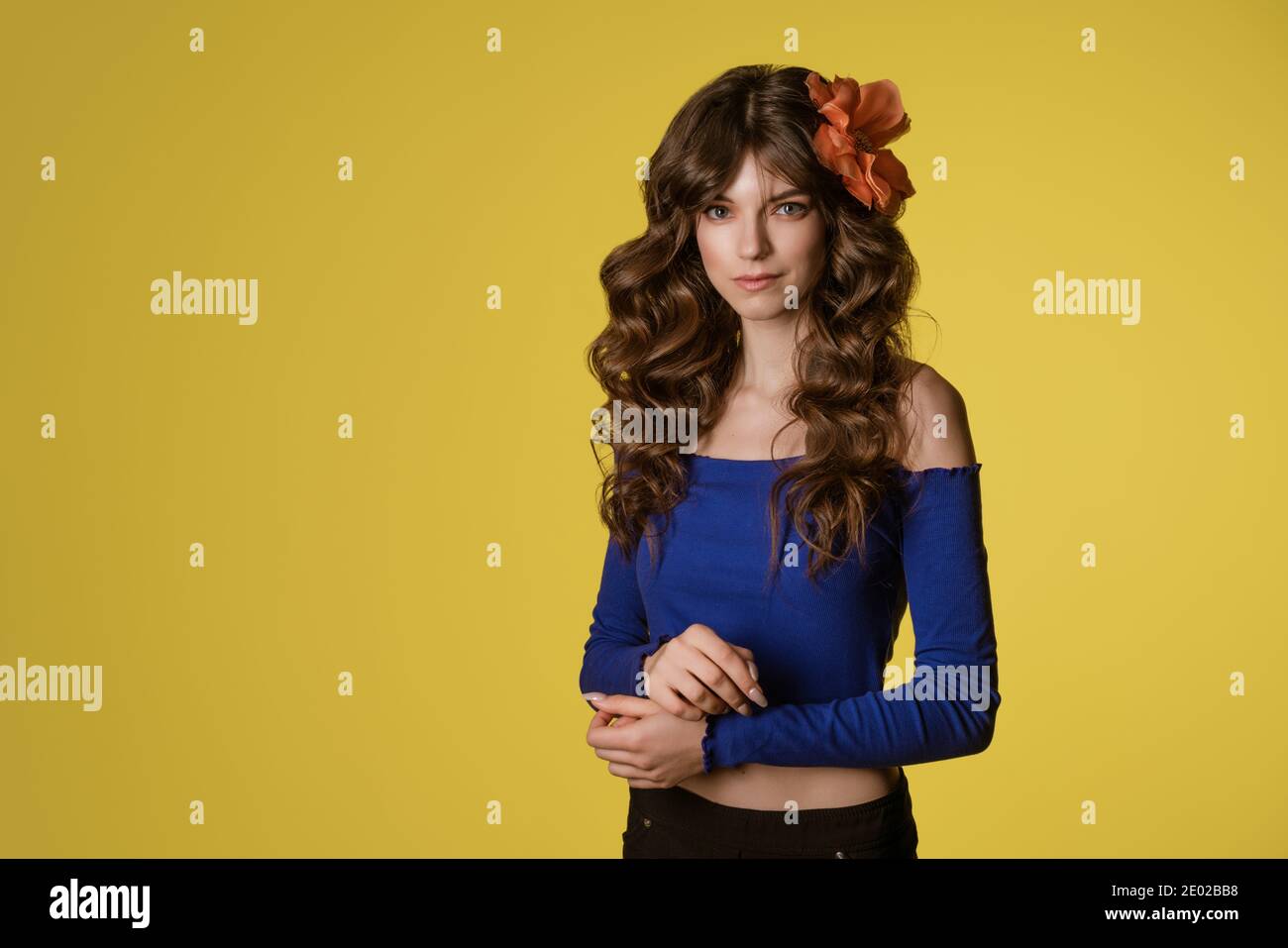 A young brunette woman with curly ears dressed in a blue top stands ...