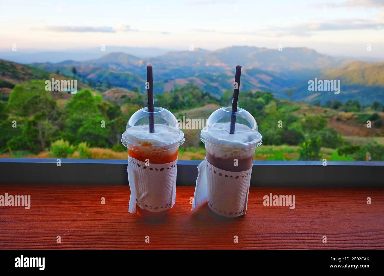 Two cold cups of ice coffee and tea on a table overlooking a beautiful ...