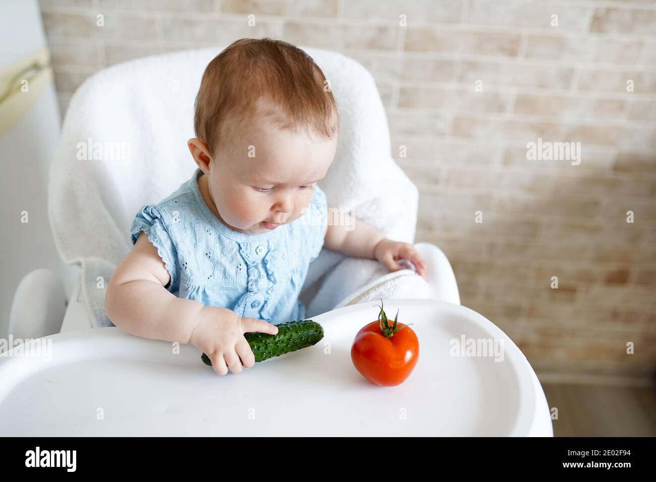 Baby eating vegetables. green cucumber in little girl hand in sunny ...