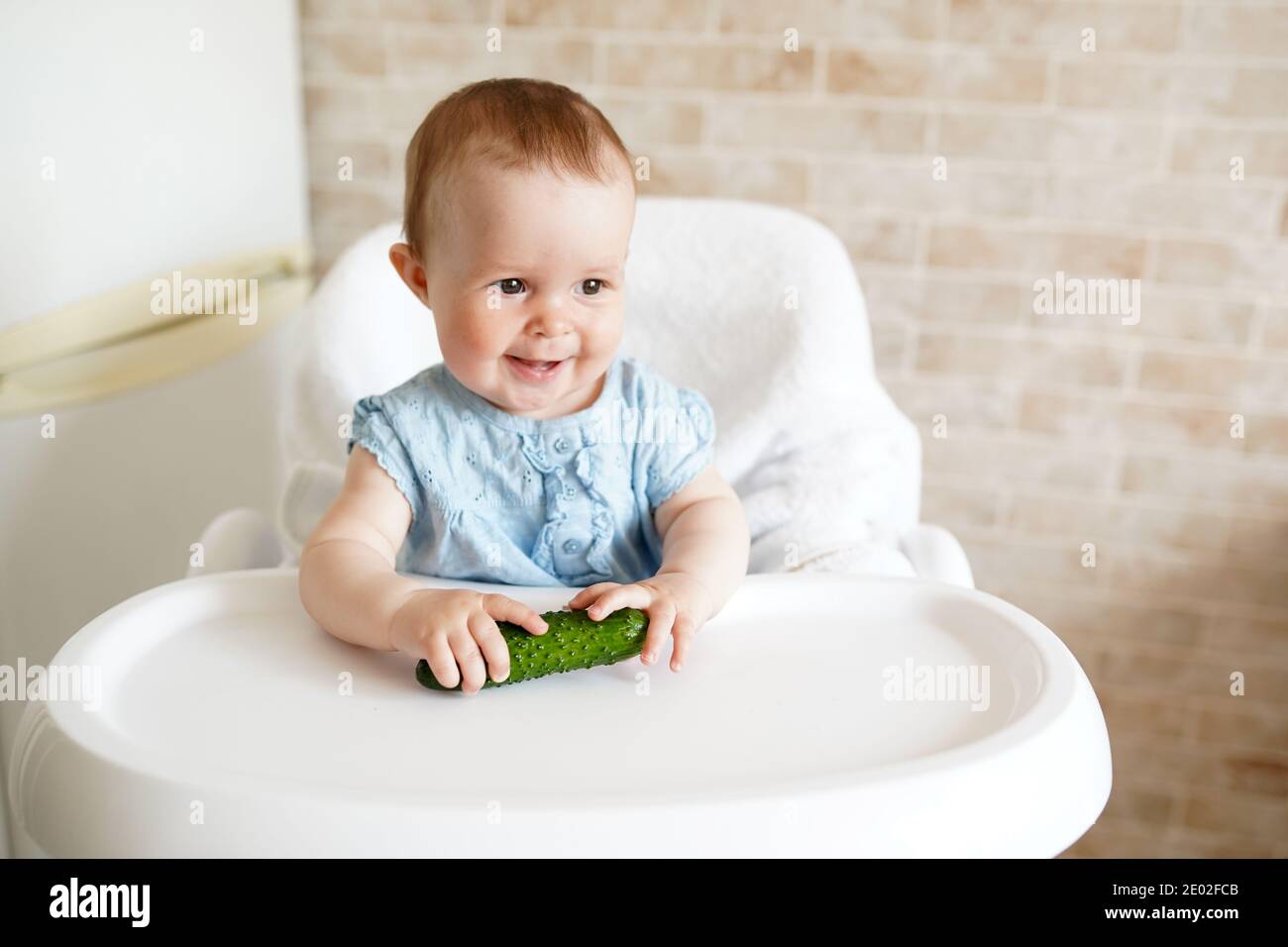 Baby eating vegetables. green cucumber in little girl hand in sunny ...