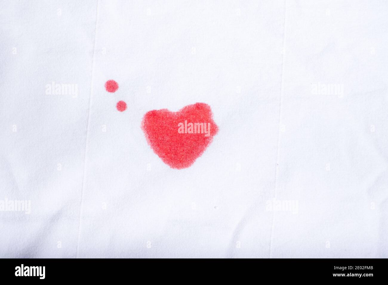 Drops of blood on a white cloth background.heart shape Stock Photo - Alamy