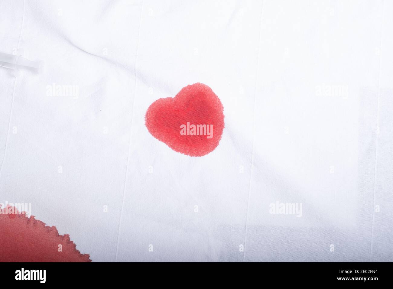 Drops of blood on a white cloth background.heart shape Stock Photo - Alamy