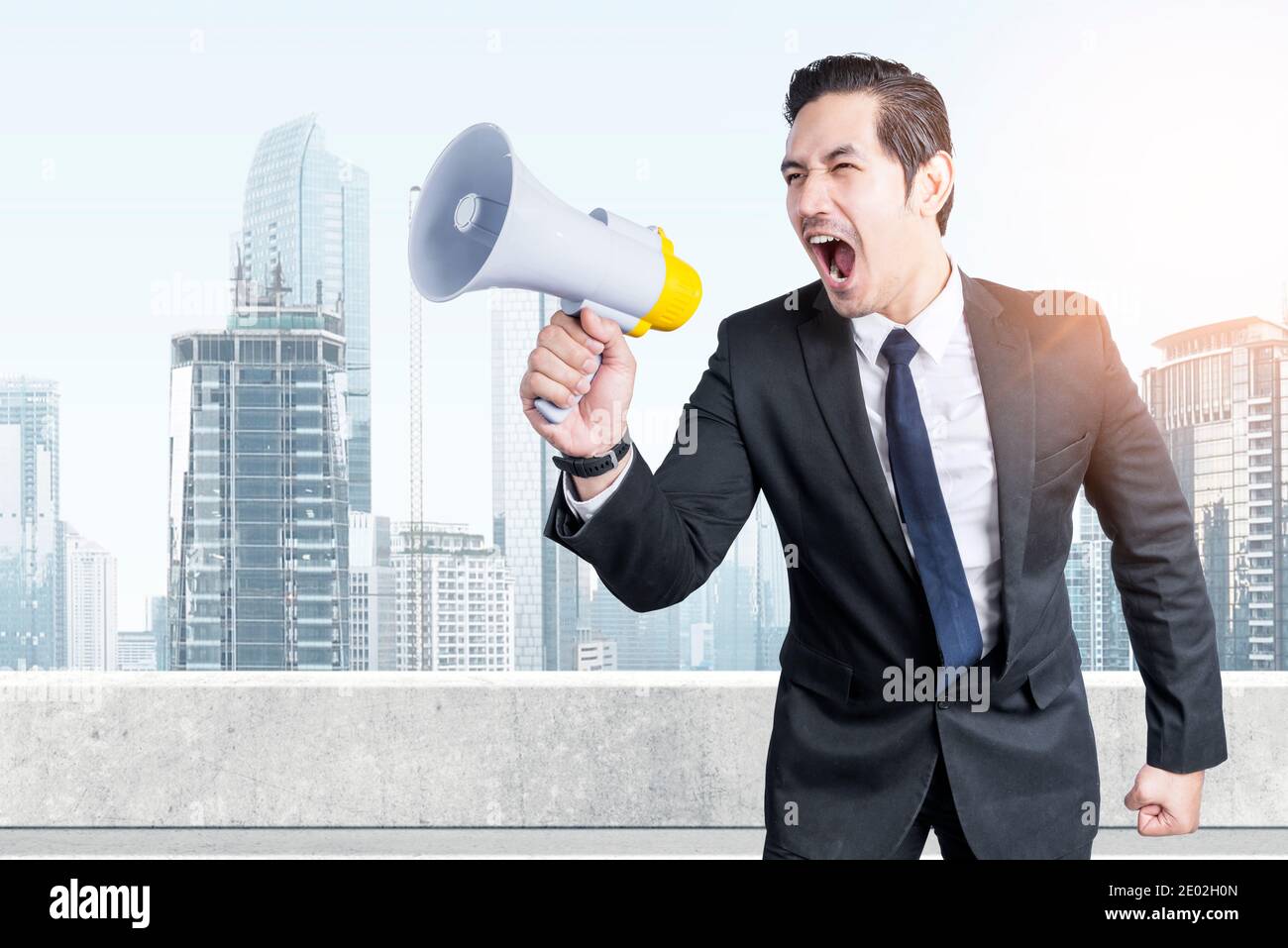 Asian businessman shouting something on megaphone with skyscrapers ...