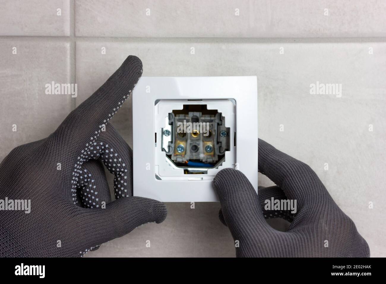 The process of installing an electrical outlet. Male hands in gray ...