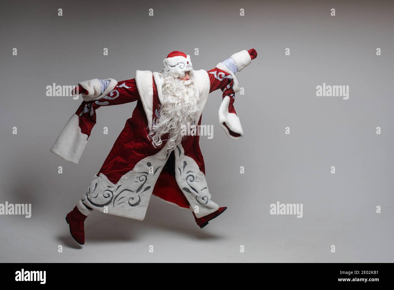 Running or jumping Santa Claus on gray studio background with copy ...