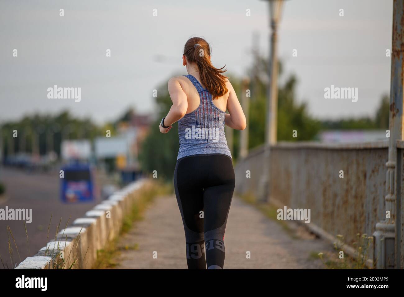 Back view of jogging young woman on the bridge Stock Photo - Alamy