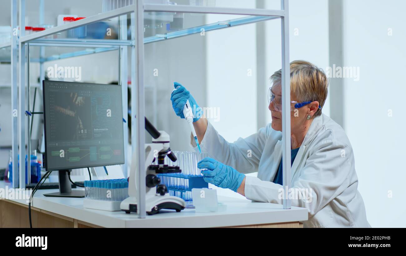 Senior scientist woman pipetting liquid to test tube in modern equipped ...