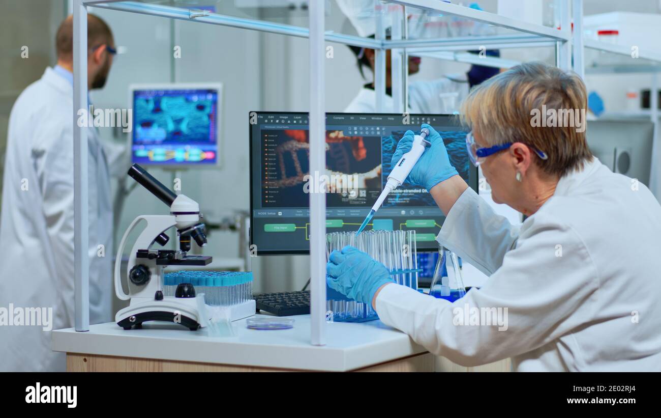 Elderly research scientist using micropipette filling test tubes in ...