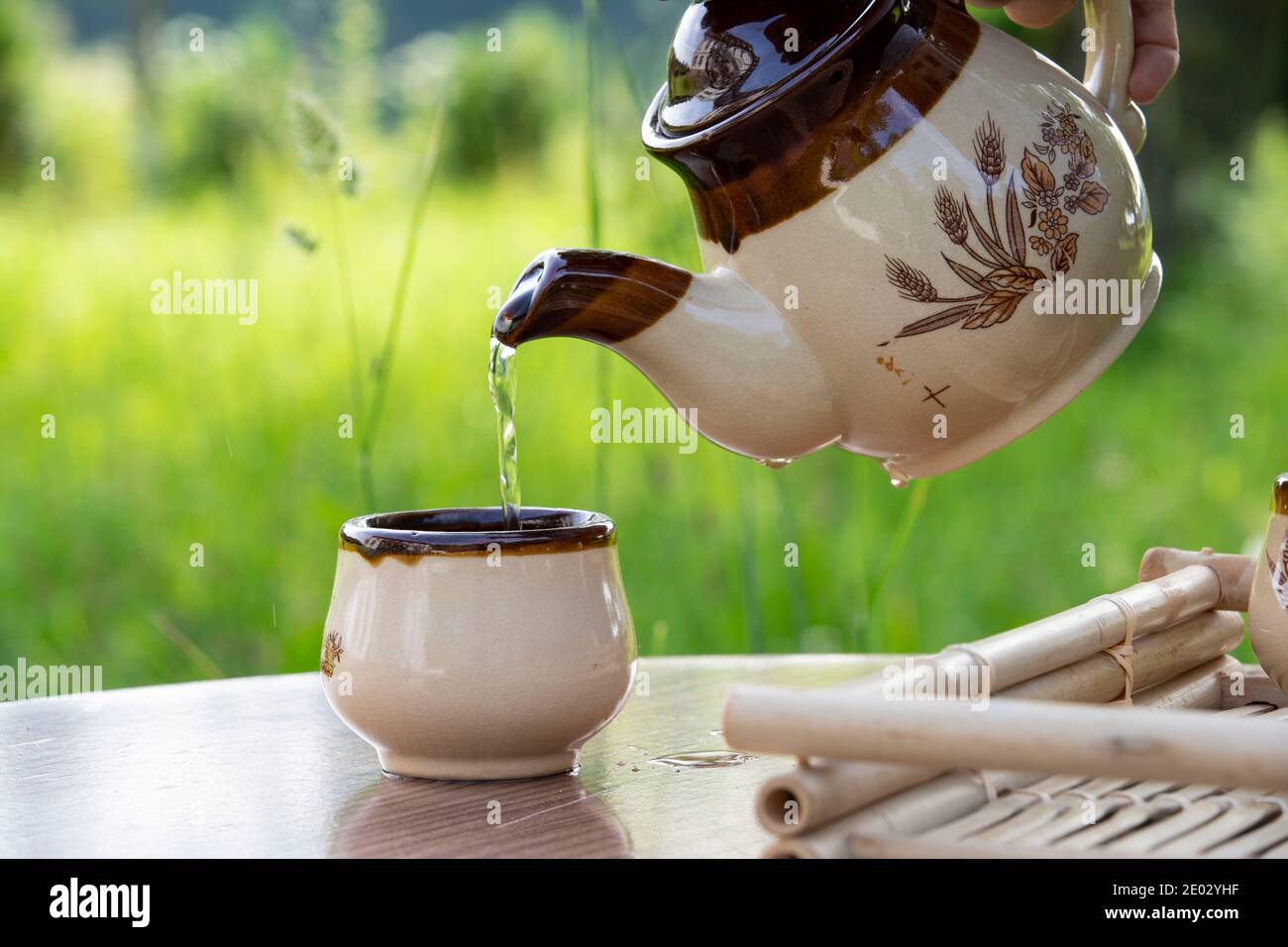 Right hand pouring tea from a vintage traditional patterned teapot to a ...