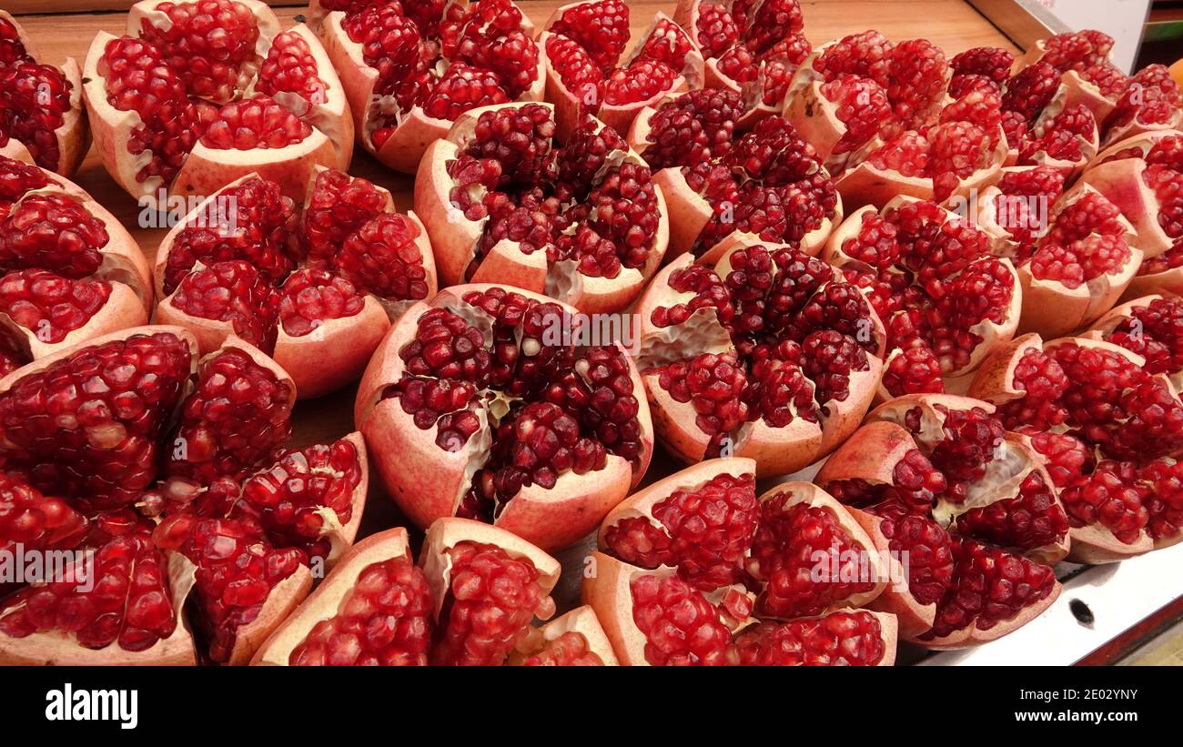 Market shelves are full of half cut-up, bright red pomegranate fruits ...