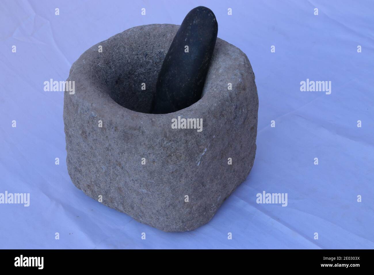 Rough stone pestle and mortar isolated on blue background Stock Photo ...