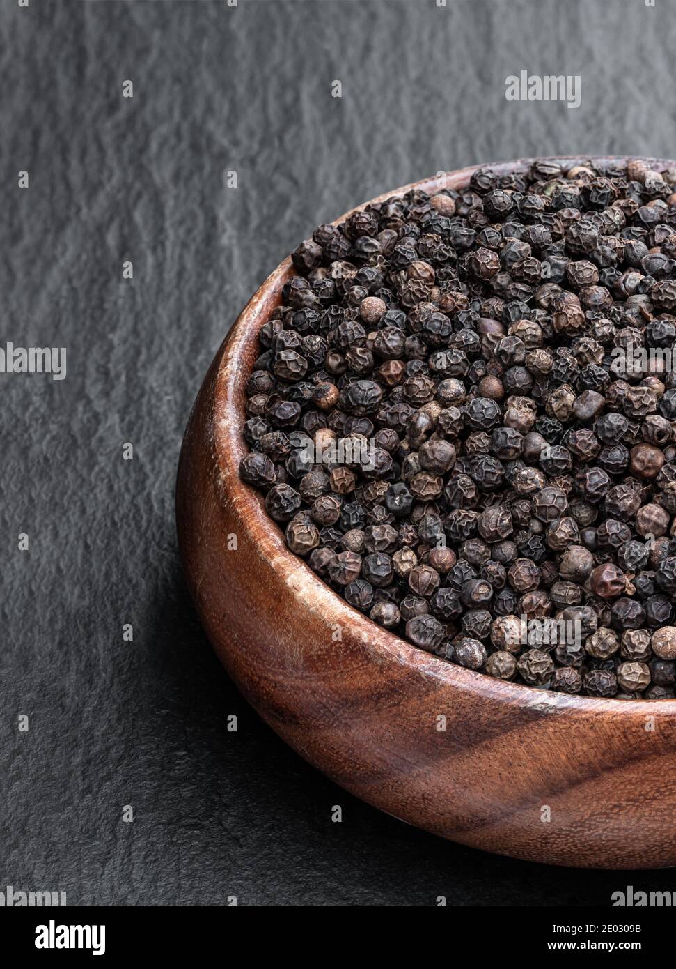Black pepper corn in wooden bowl on black stone background Stock Photo ...