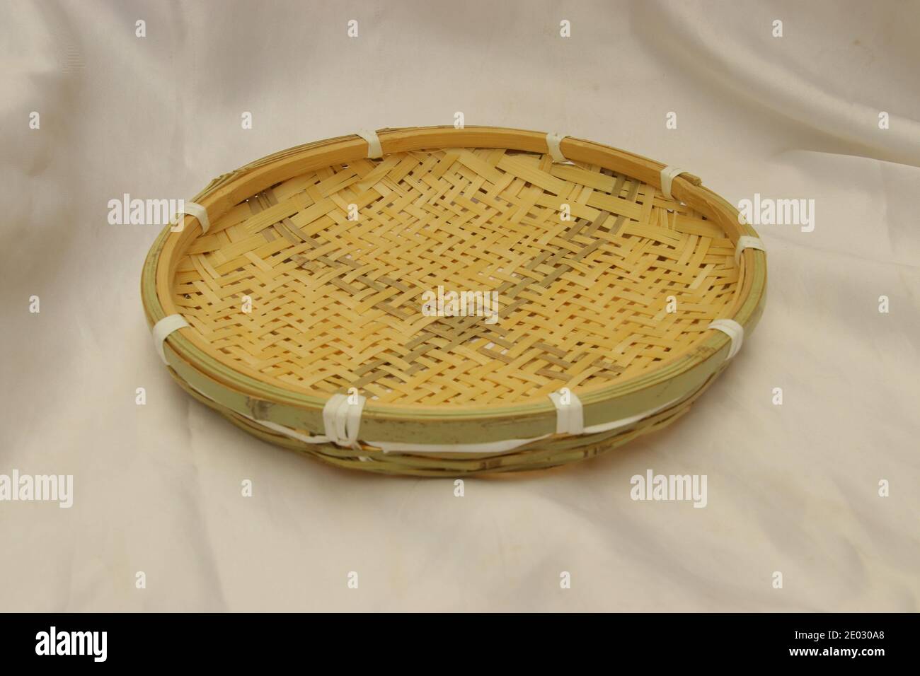 Round empty handmade bamboo sieve with green trim and crosshatching ...