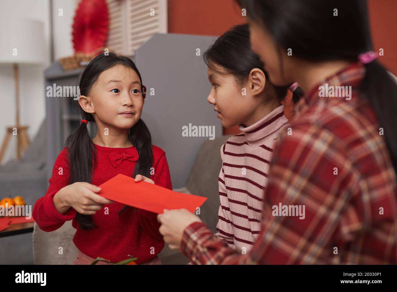 Over-the-shoulder shot of Chinese woman gifting envelope with money to ...