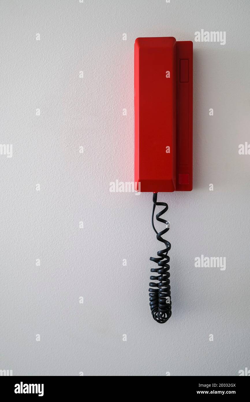 Red emergency phone on white wall Stock Photo - Alamy