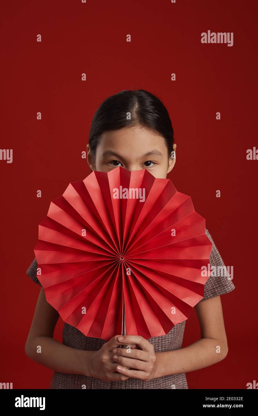 Unrecognizable Asian girl standing against red wall background holding ...