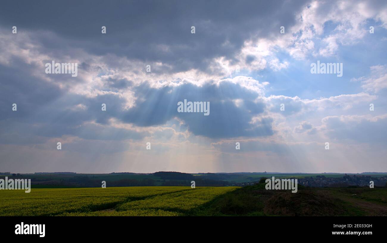 Sunbeams shining through dark clouds on spring green fields Stock Photo ...