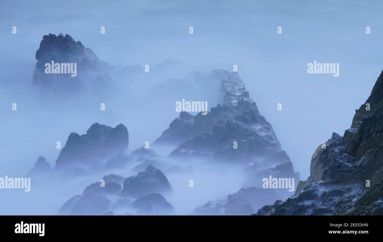 Fog covered rocks near lighthouse in Brest of France in early morning ...
