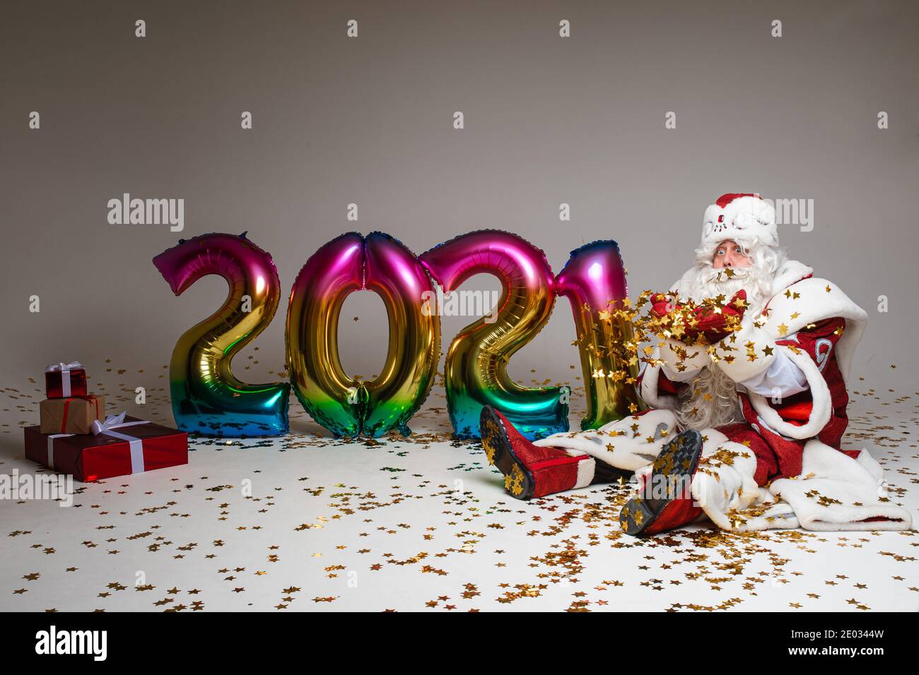 old father frost with colourful baloons with numbers 2021 holds a gift ...