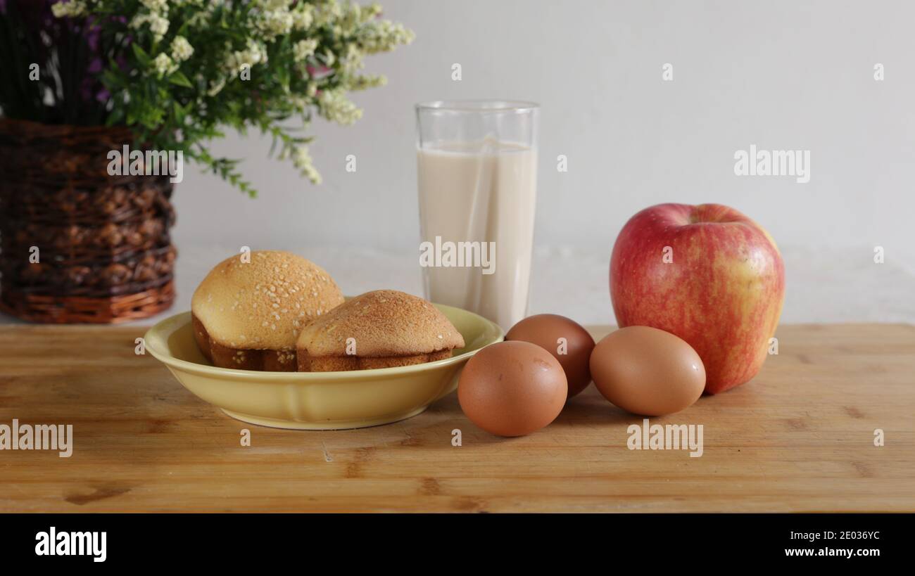 Nutrient breakfast, milk, eggs, bread, apple on wooden table, white ...