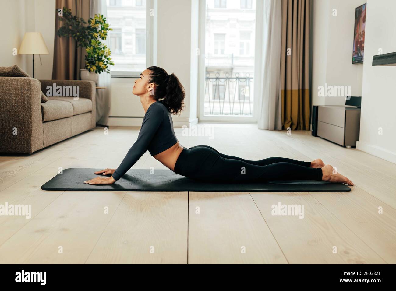 Side view of woman doing stretching exercises on mat at home Stock ...