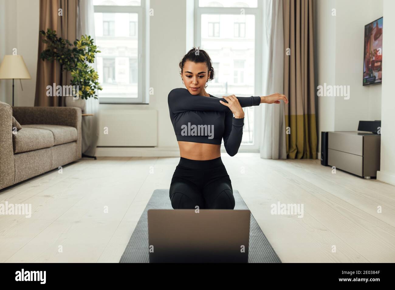 Young woman repeating exercises while watching online exercise session ...