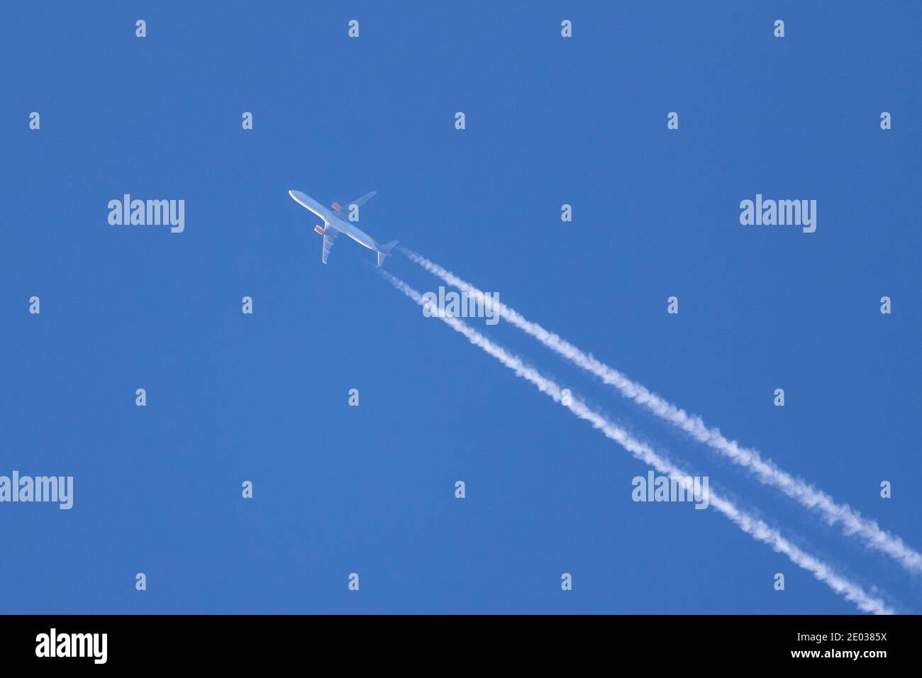 A portrait of an airplane flying through the sky with the condensation ...