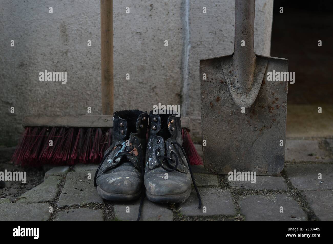 old worn painted work boots with a yard broom and a spade as symbol for ...