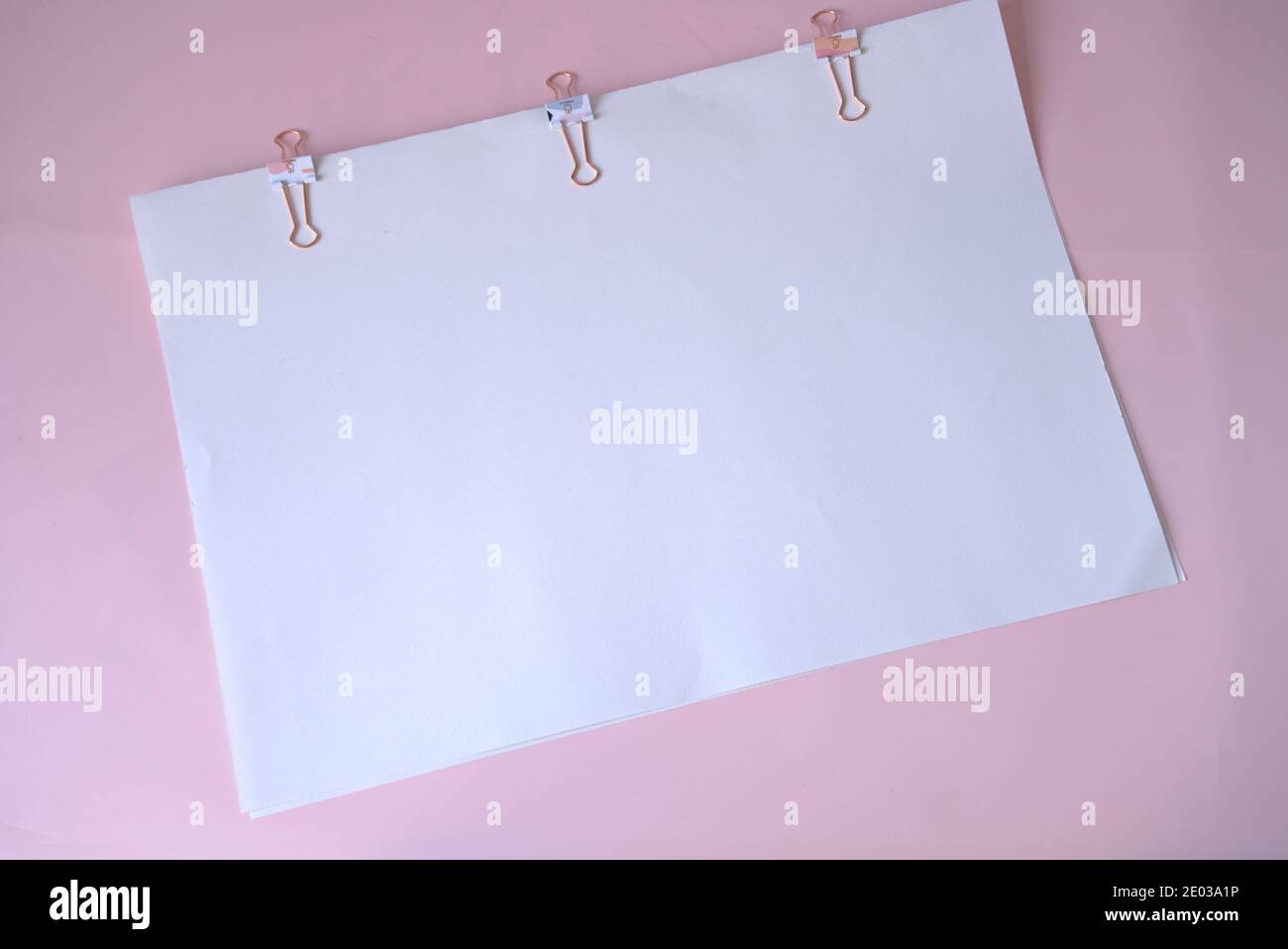 White paper with binder clips on pastel background, blank for your text ...