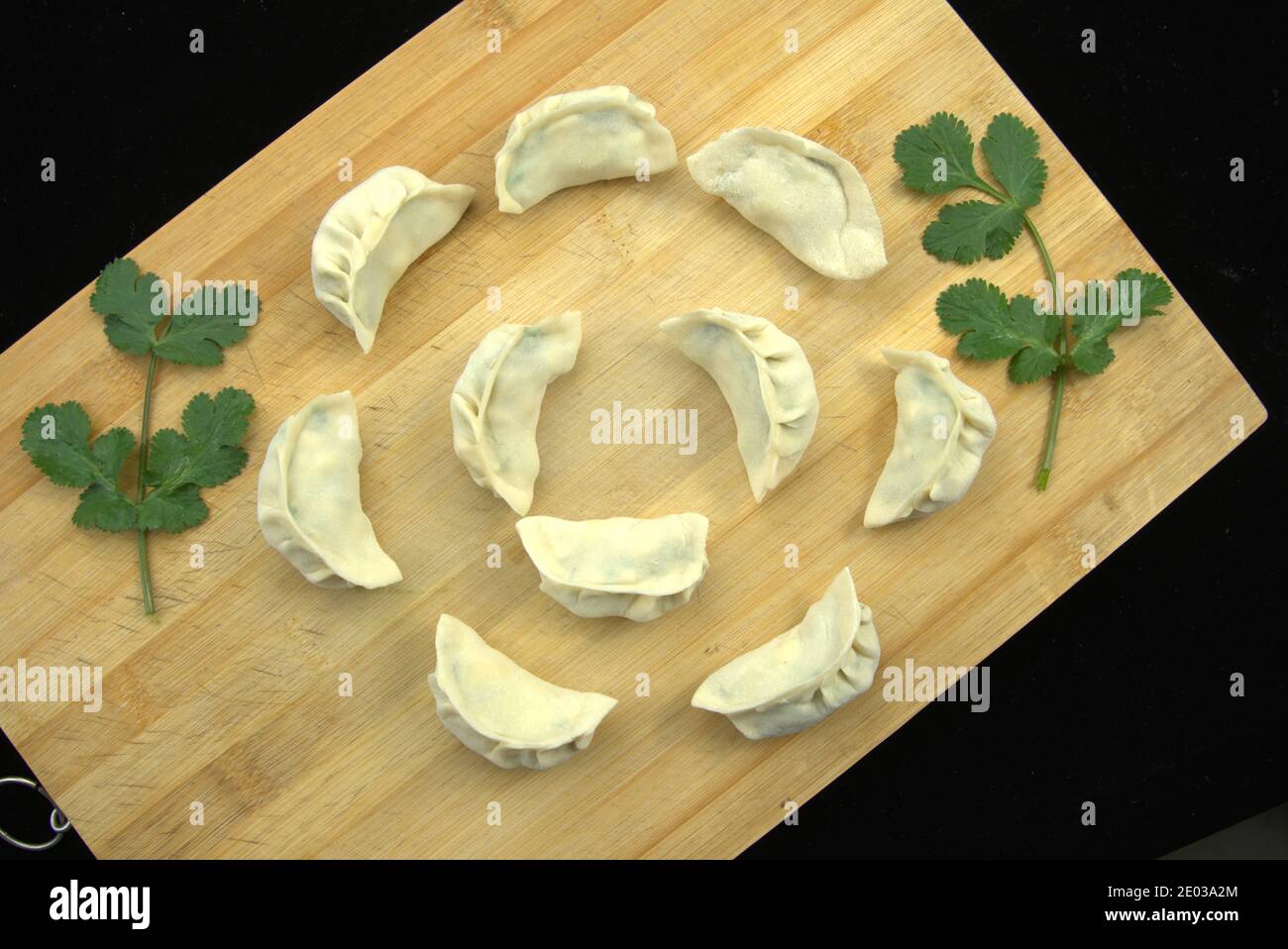 Raw dumplings on cutting board arranged in flower shape, black ...