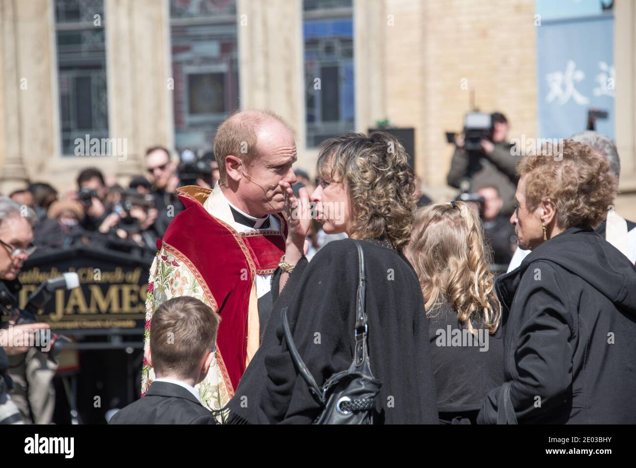 Rev. Canon Andrew Asbil greets and talks to Renata Ford and children ...