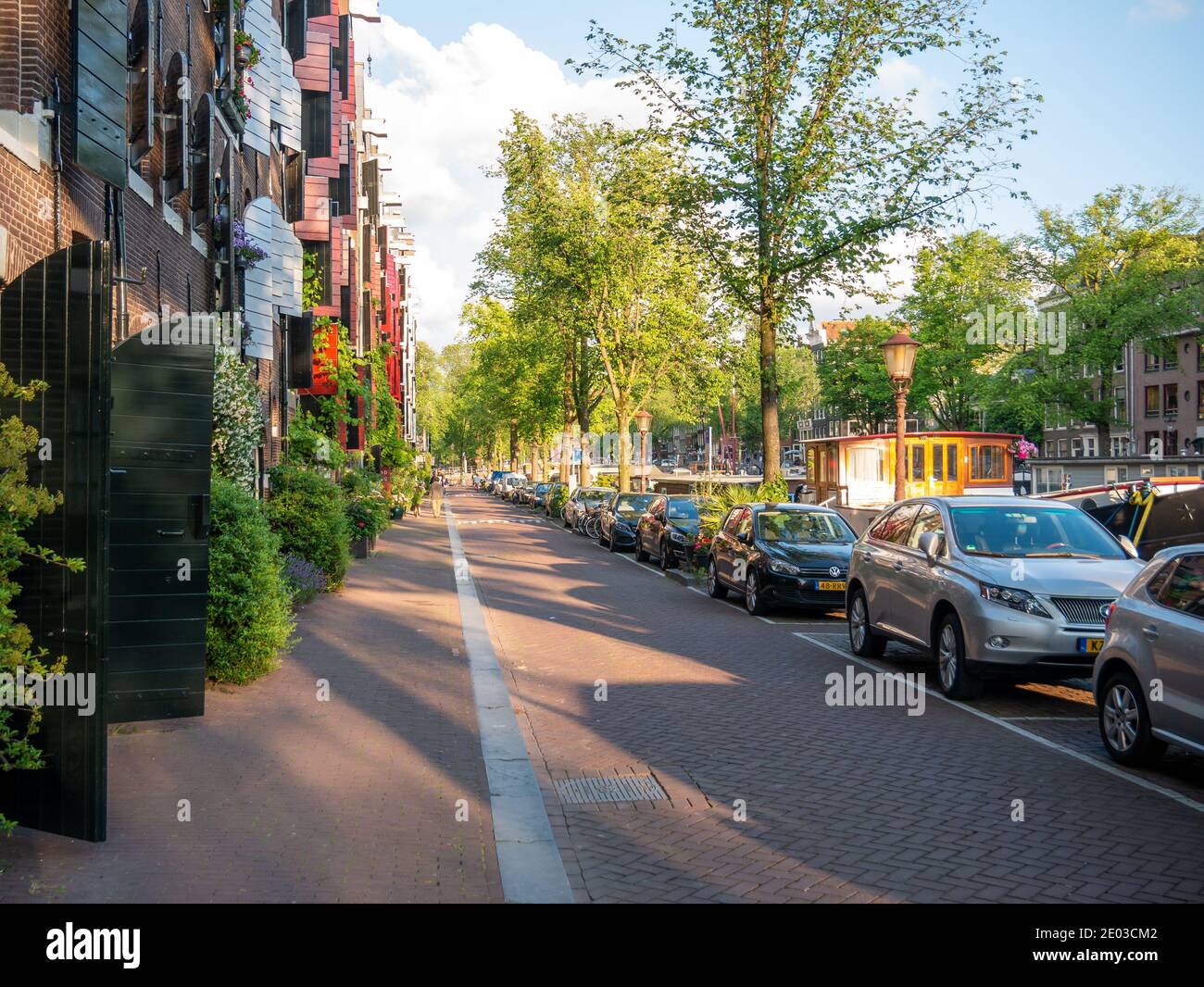 Amsterdam, Netherlands - June, 2019. A narrow city street with cars ...
