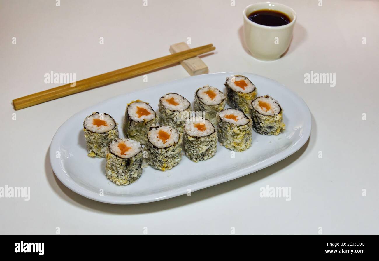 Japanese sushi rolls on white long porcelain plate on white table, top ...