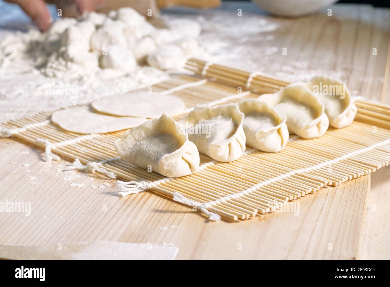 Dumplings and dumpling skins on bamboo mat, blur background, Chinese ...