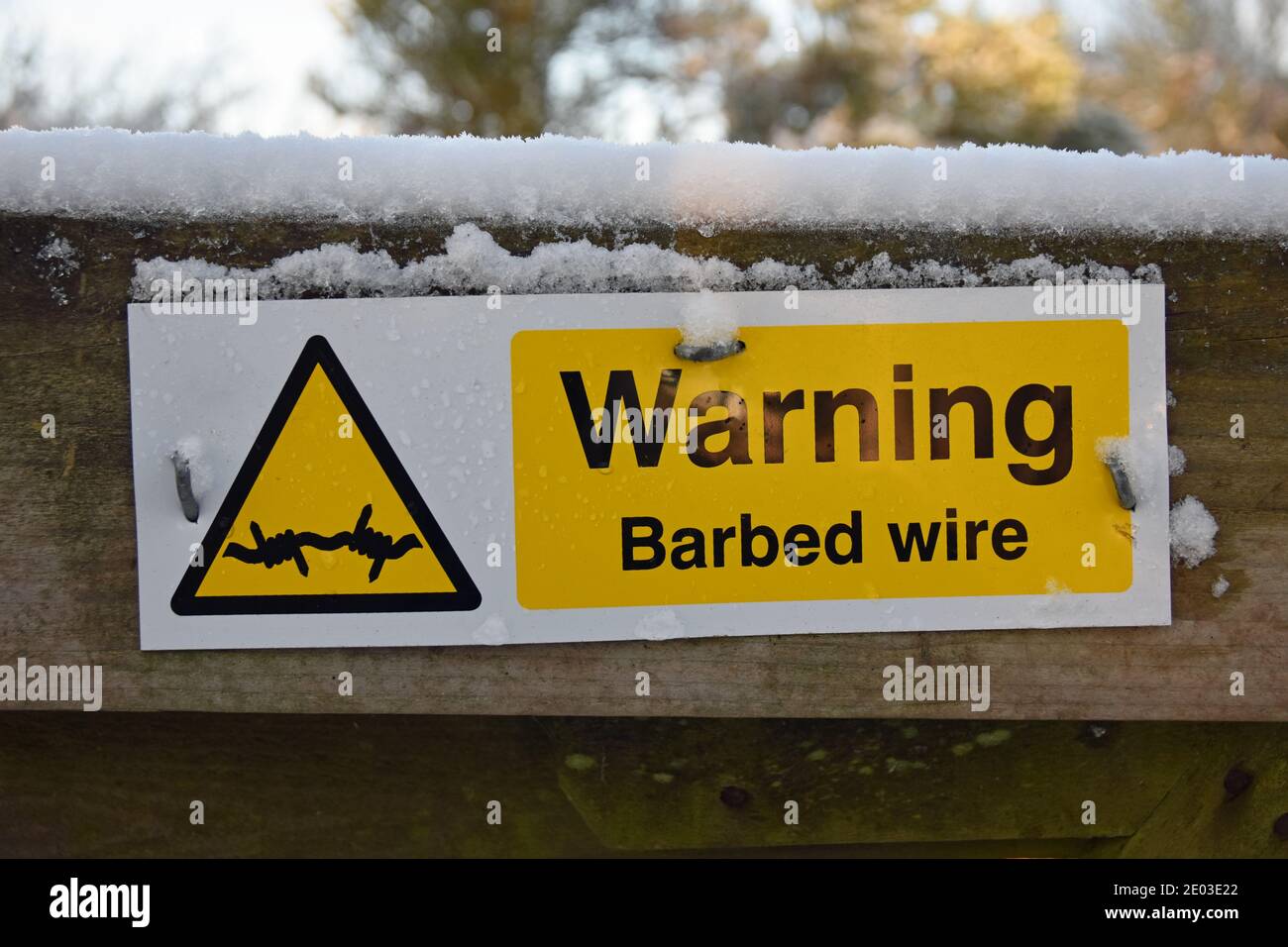 Yellow, black and white rectangular sign: warning barbed wire with ...