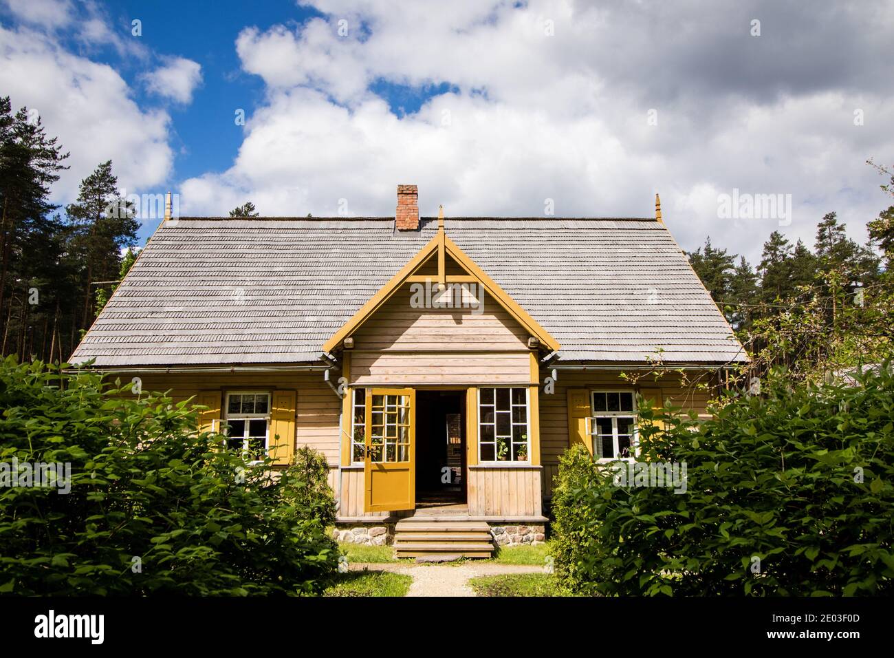 Beautiful baltic wooden house with main door open, sunny day, trees ...