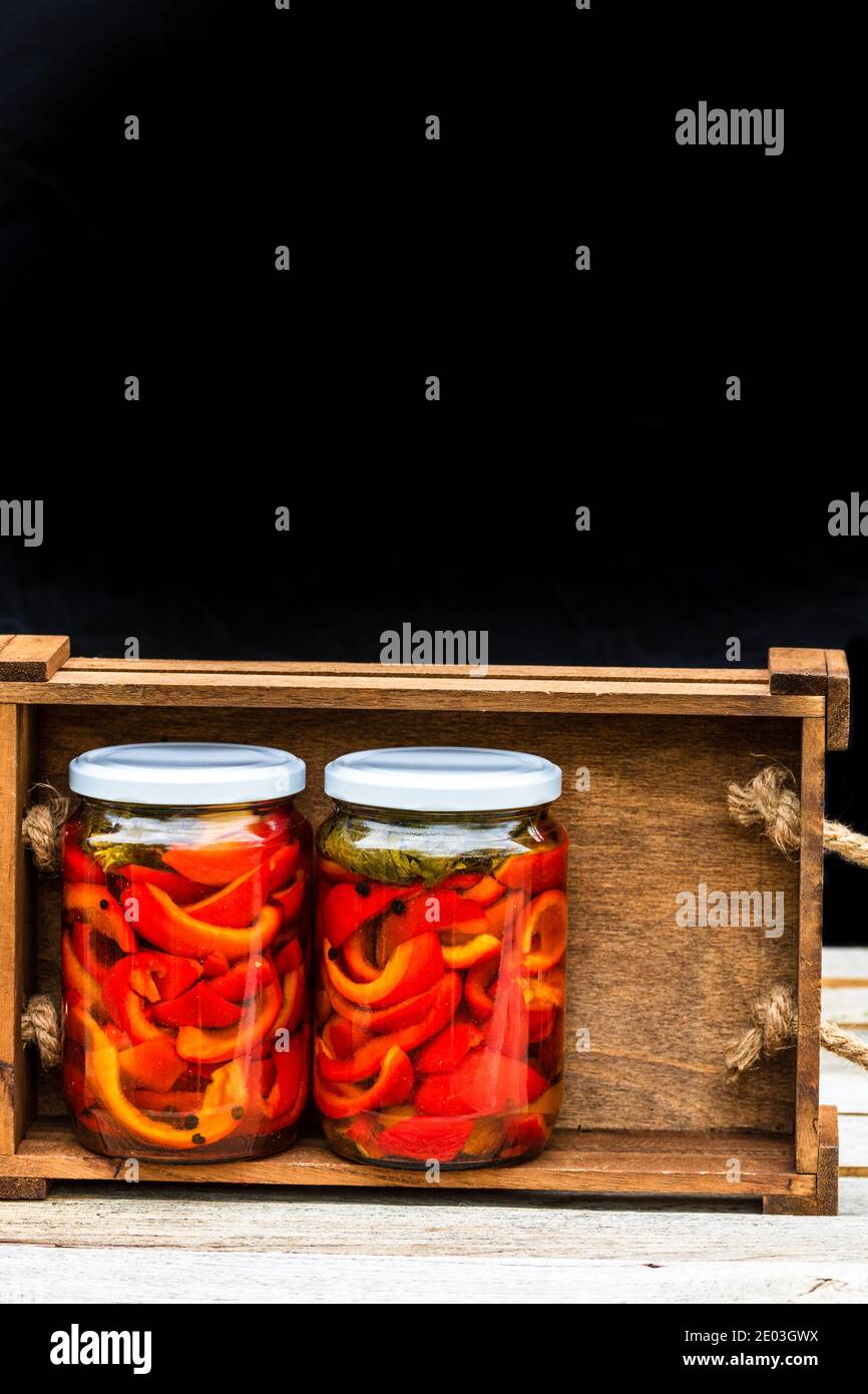 Wooden crate with glass jars with pickled red bell peppers.Preserved ...