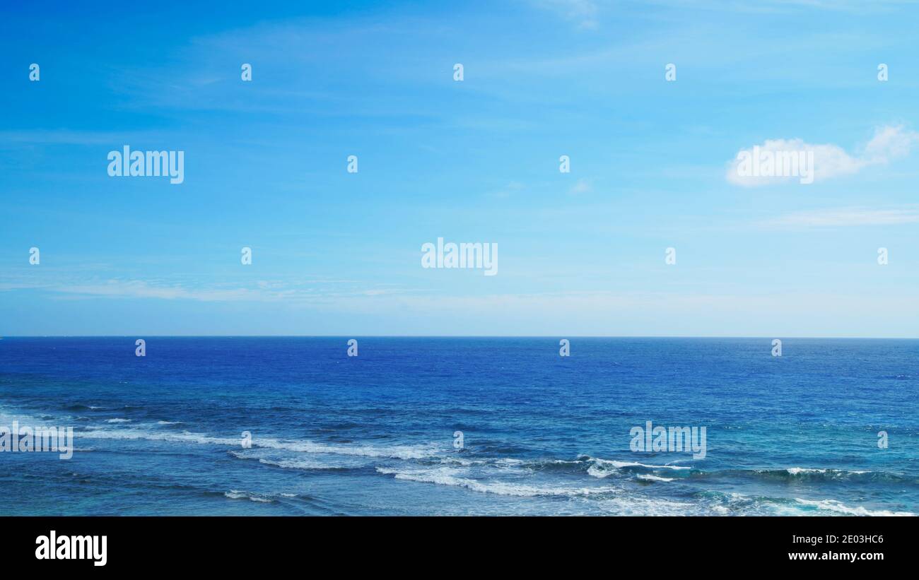 Horizon seascape with blue sky, waves on the water of a sandy beach ...