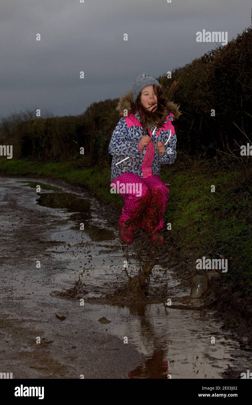 Young girl jumping into muddy puddles. England Stock Photo - Alamy