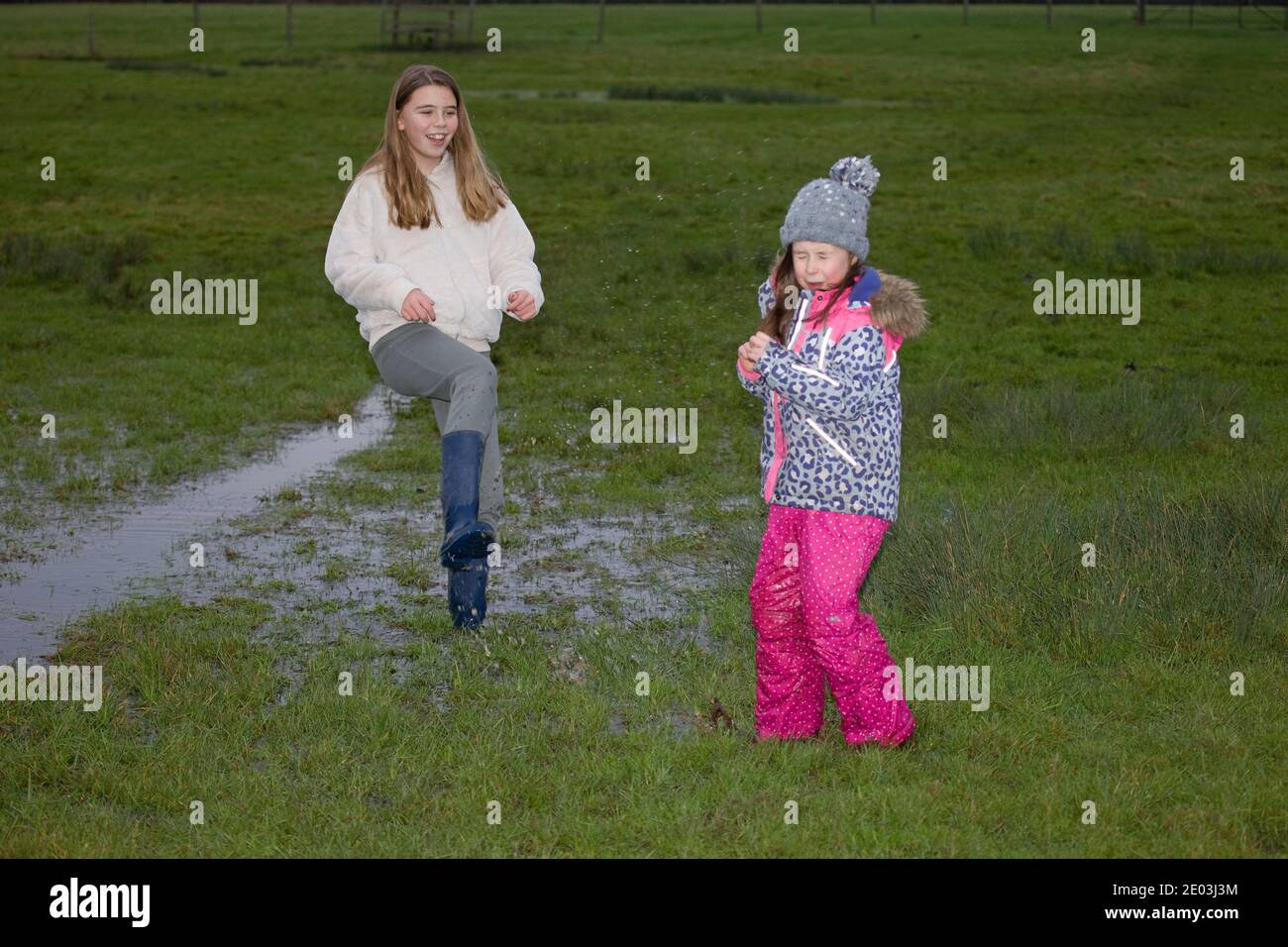Young girls playing in muddy puddles. England Stock Photo - Alamy