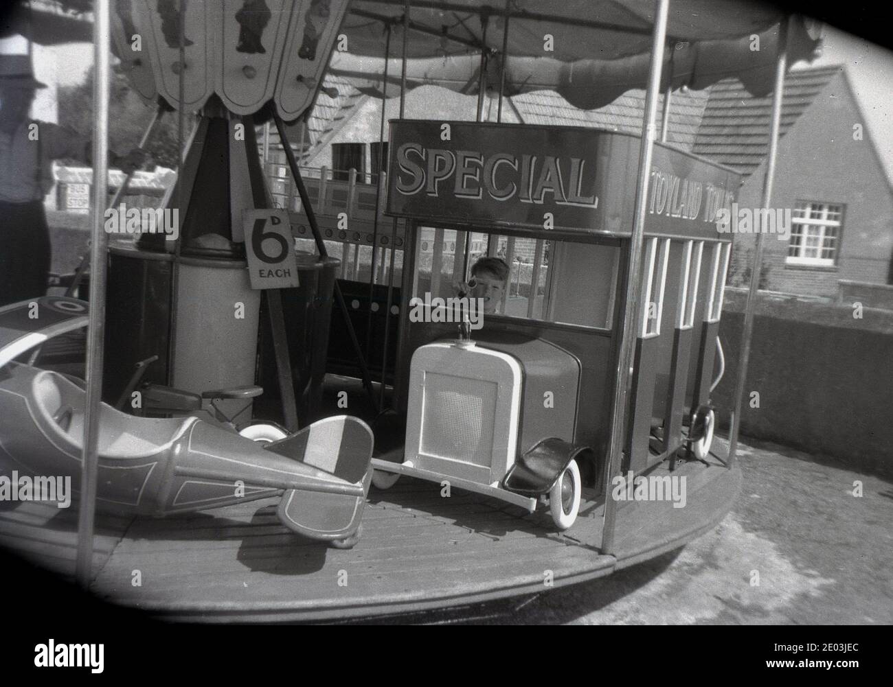 1960s, historical, a young boy sitting on a 'bus' on a small fairground ...