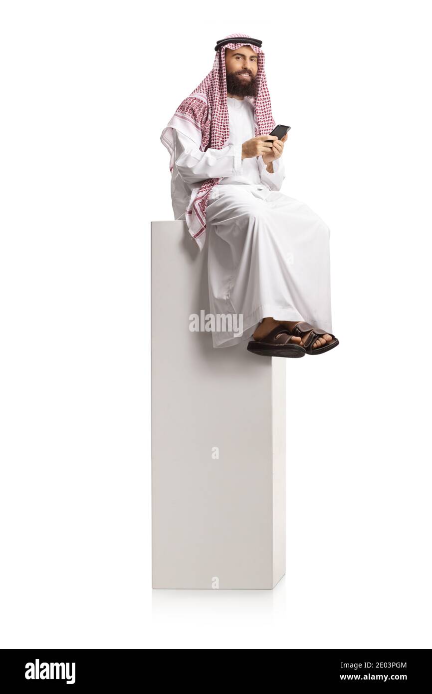 Saudi arab man holding a smartphone and sitting on a tall white column ...