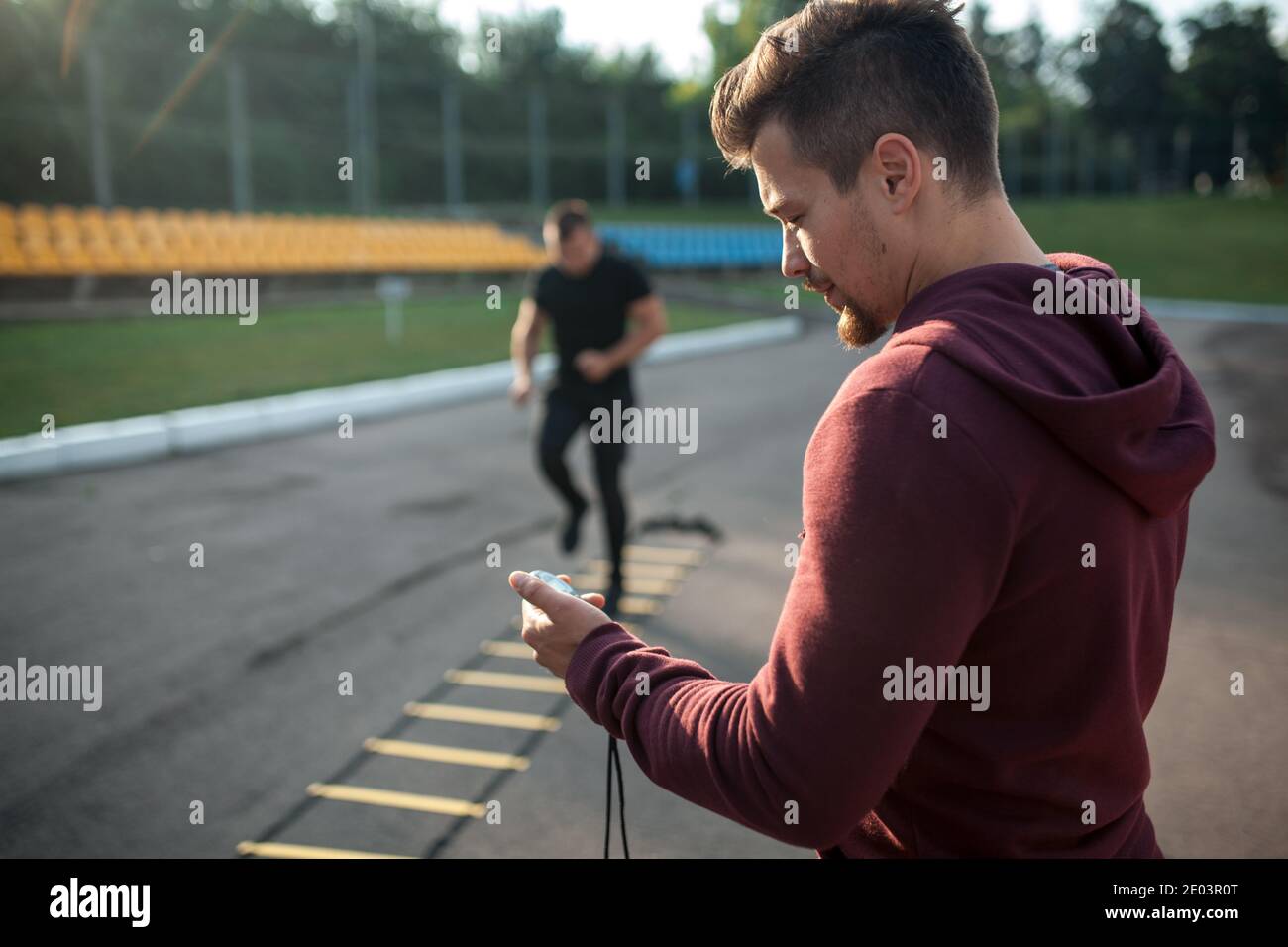 personal trainer with stopwatch measuring time of male exercising ...